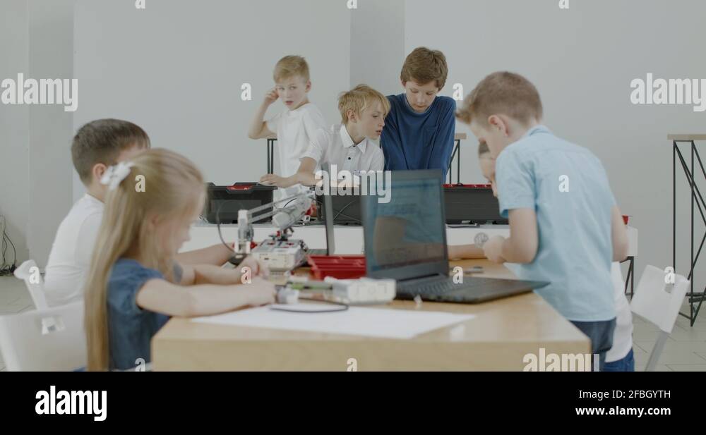 Curious kids working on a programable robot during robotics class at ...