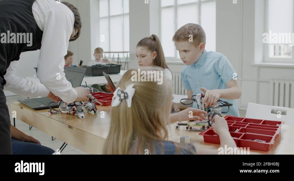 Curious kids working on a programable robot during robotics class at ...