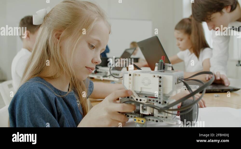 Curious kids working on a programable robot during robotics class at ...