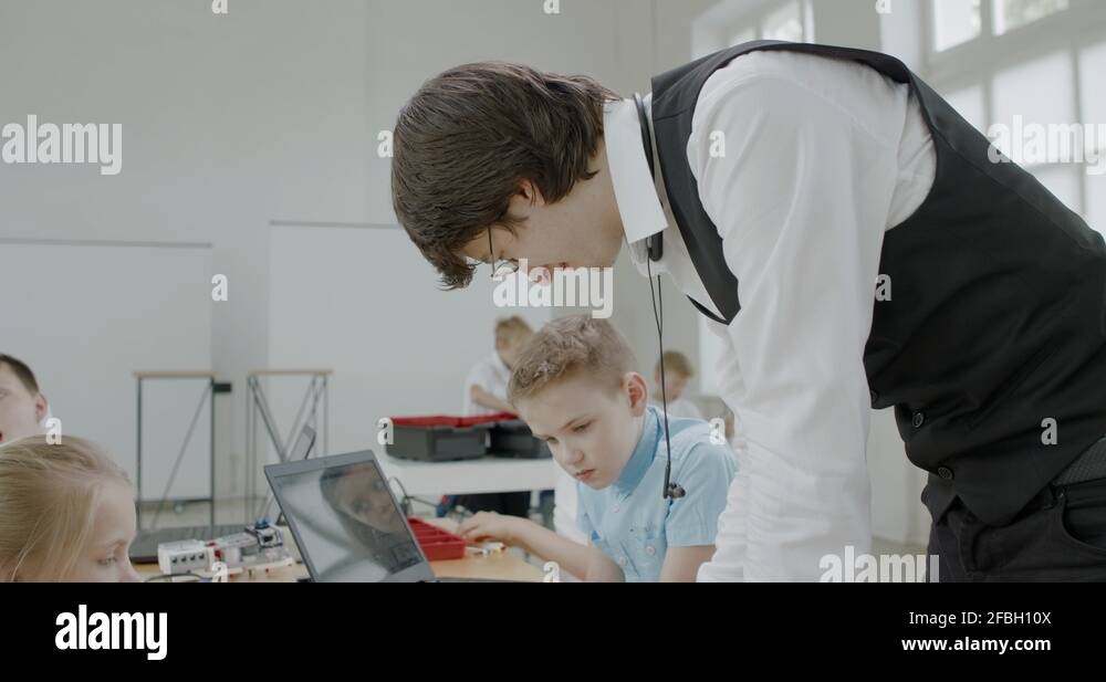 Curious kids working on a programable robot during robotics class at ...