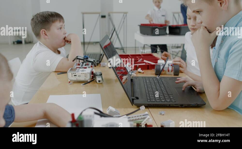 Curious kids working on a programable robot during robotics class at ...