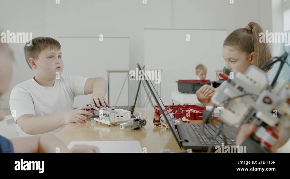 Curious kids working on a programable robot during robotics class at ...