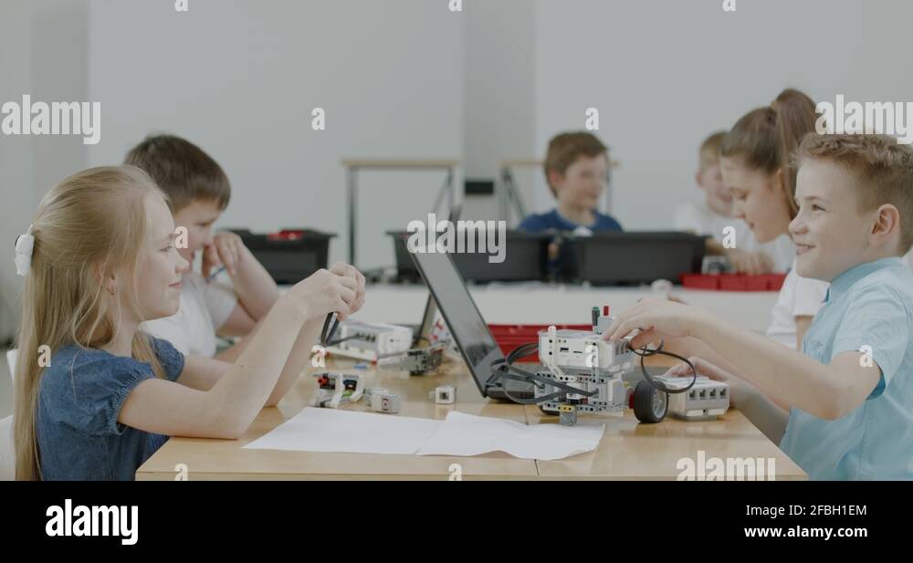 Curious kids working on a programable robot during robotics class at ...