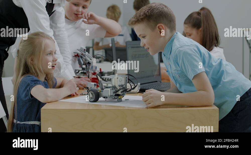 Curious kids working on a programable robot during robotics class at ...