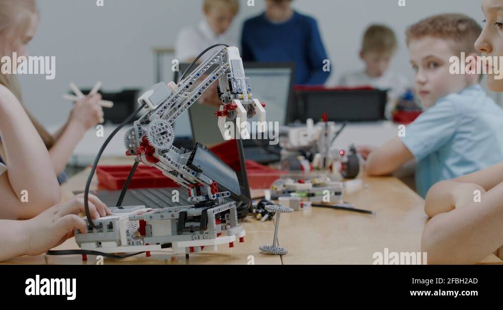 Curious kids working on a programable robot during robotics class at ...