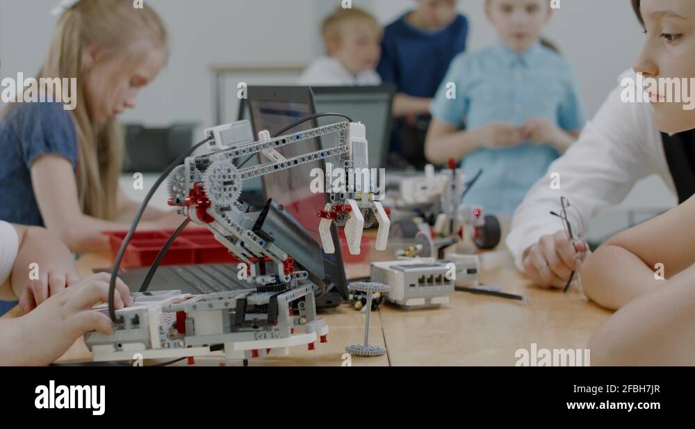 Curious kids working on a programable robot during robotics class at ...