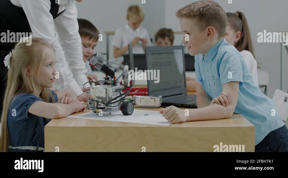Curious kids working on a programable robot during robotics class at ...