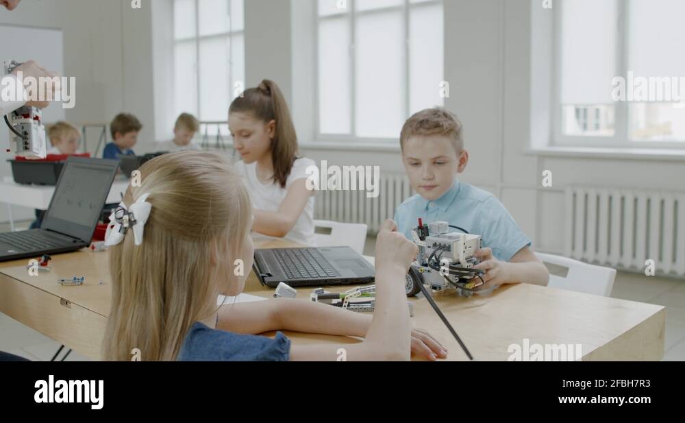 Curious kids working on a programable robot during robotics class at ...
