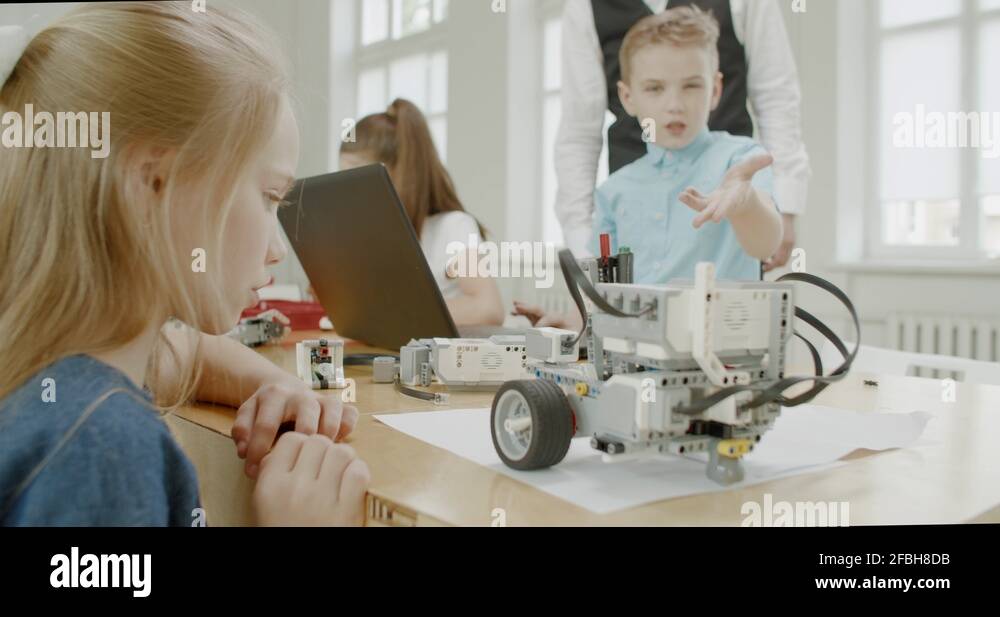 Curious kids working on a programable robot during robotics class at ...