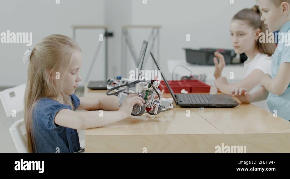 Curious kids working on a programable robot during robotics class at ...