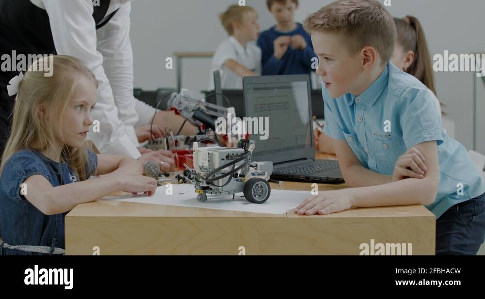 Curious kids working on a programable robot during robotics class at ...