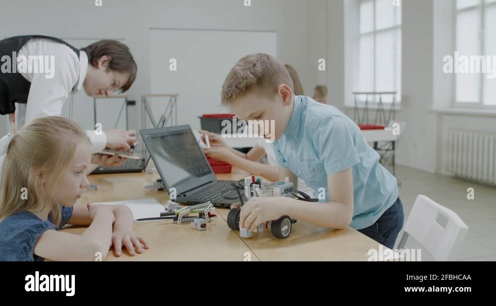 Curious kids working on a programable robot during robotics class at ...