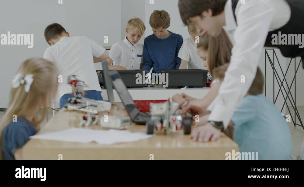 Curious kids working on a programable robot during robotics class at ...