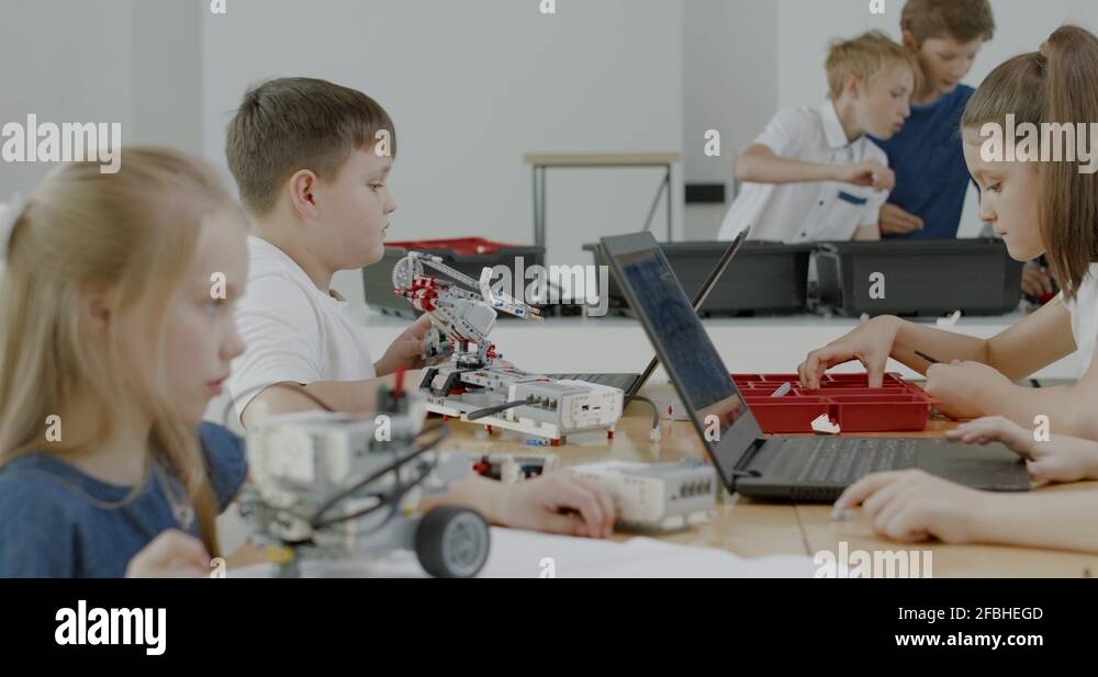 Curious kids working on a programable robot during robotics class at ...