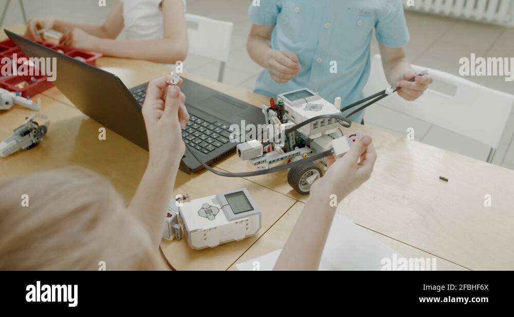 Curious kids working on a programable robot during robotics class at ...