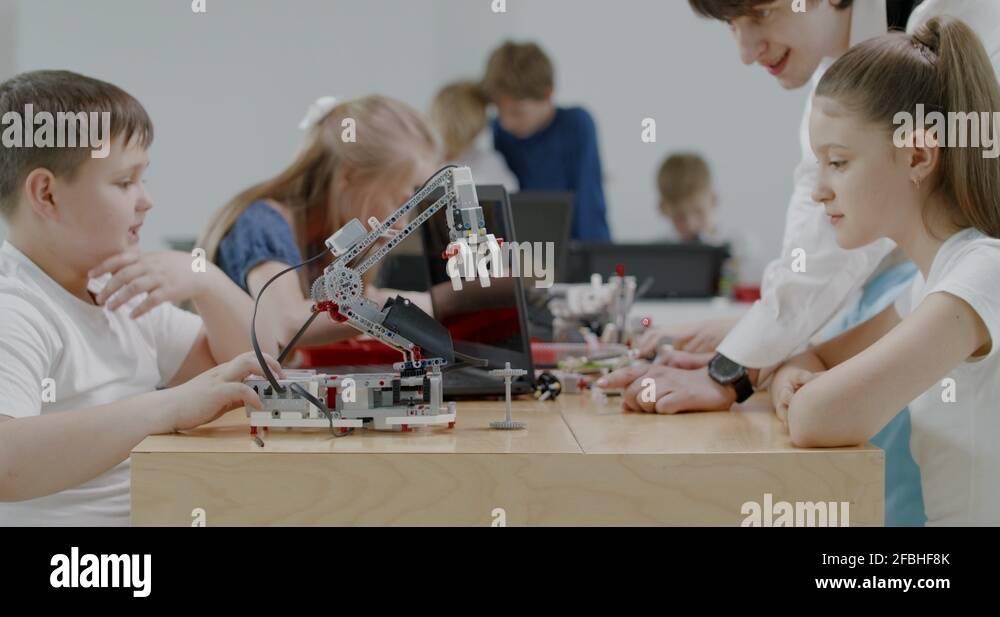 Curious kids working on a programable robot during robotics class at ...