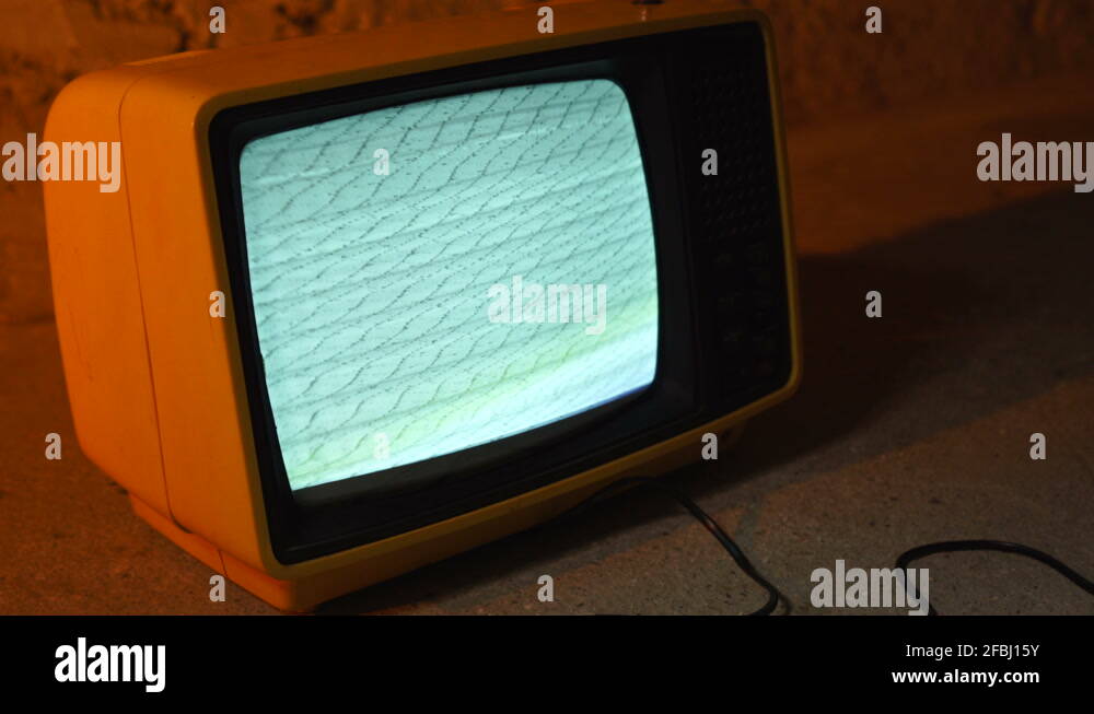 Unplugged old TV with flickering television screen on floor in dark ...
