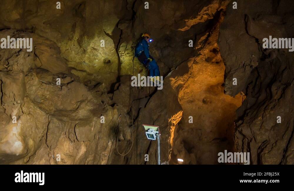 A person who was climbing in a cave is now slowly going on on a rope ...