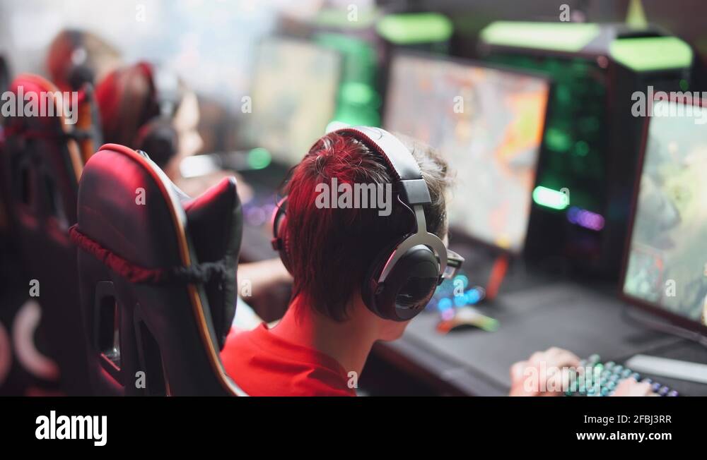 Young gamer plays a video game, side view, typing on keyboard ...