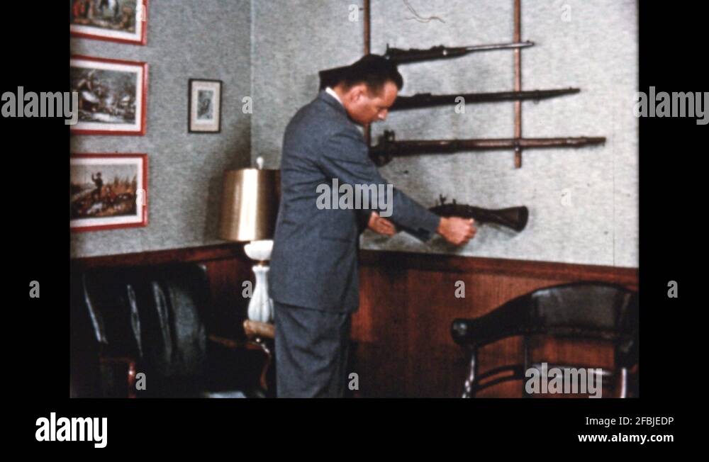 1940s: Man takes gun from rack. Close up, hand touches parts of gun ...