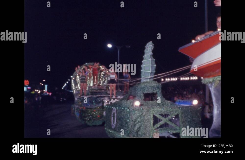 1960s: Women in swimsuits wave from parade float. Woman in formal gown ...