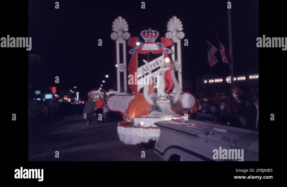1960s: Miss Hawaii waves from parade float. Women seated on parade ...