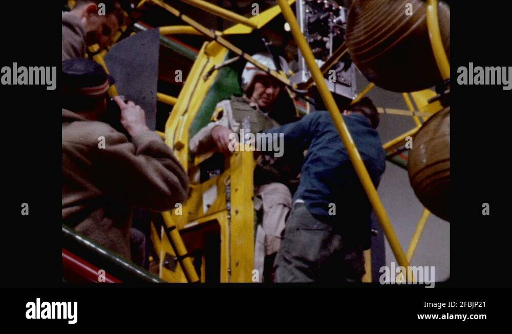 1960s: Low angle, man strapping Wally Schirra into flight simulator ...