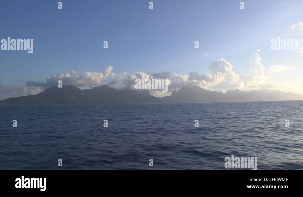 Distant island with clouds above it view froming boat in the ocean in ...