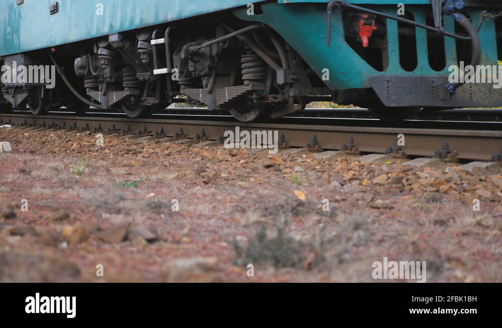 Close up spinning steel wheels of the train moving along the rail track ...