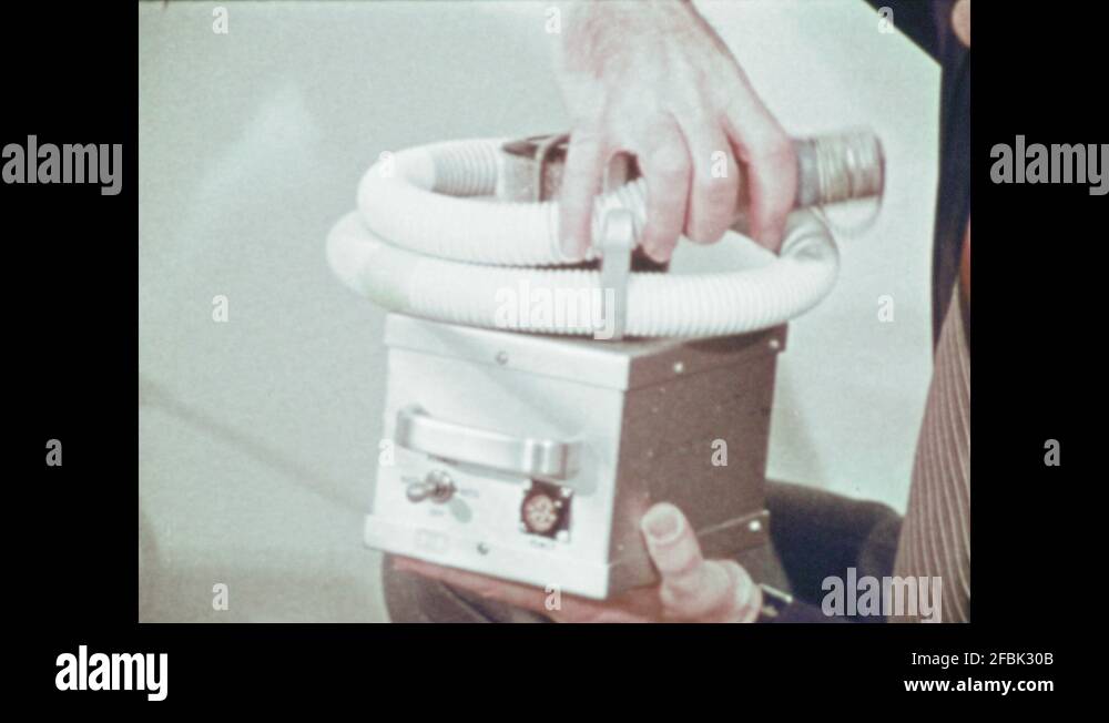 1970s: Man holds back up battery box, flips switch. Men exit vehicle ...