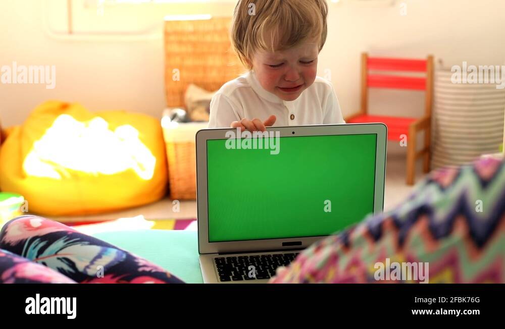 Crying caucasian little boy closing laptop notebook with green screen ...