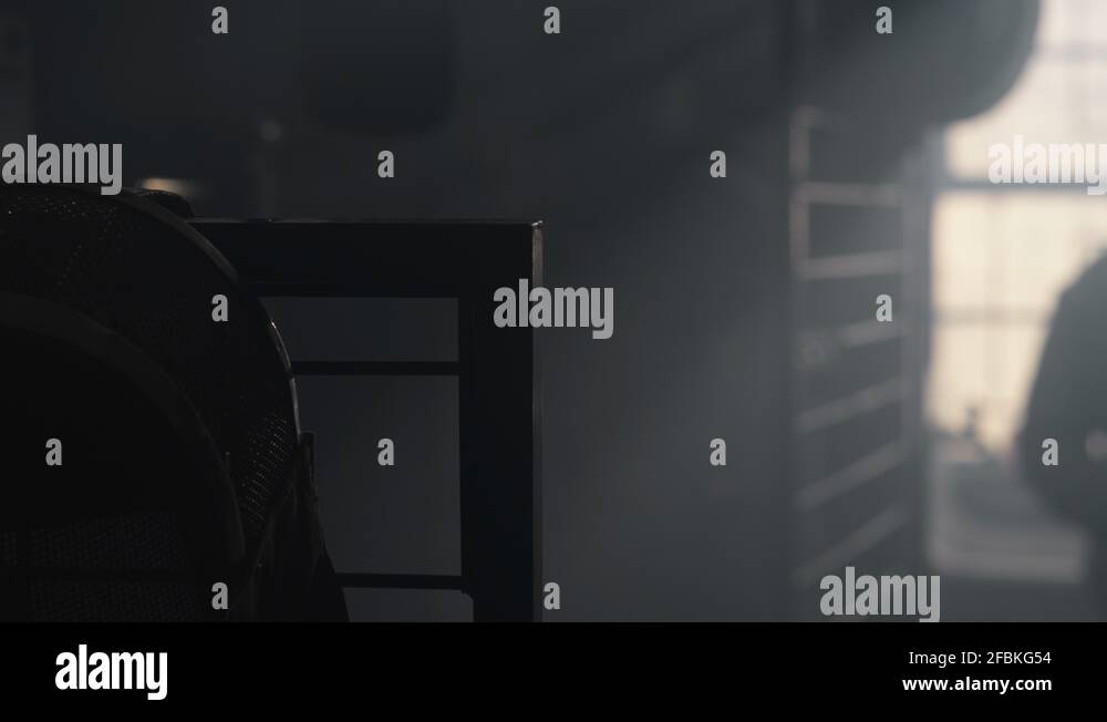 A fencer checks out his fencing foil in a dark and dusty locker room ...