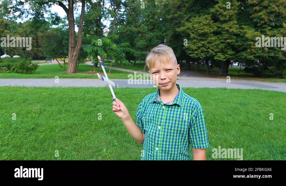 Kid playing wooden boomerang outdoors in green park. Boy throwing ...