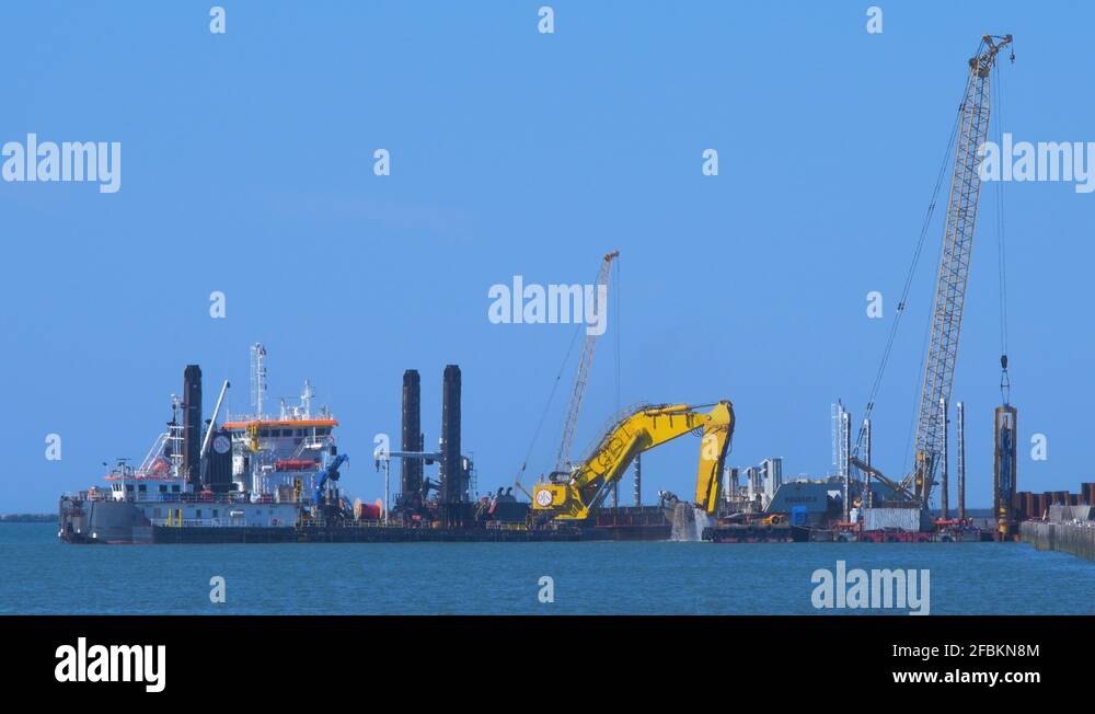 Hopper dredger ship working at Port of Liepaja, crane with bucket lifts ...