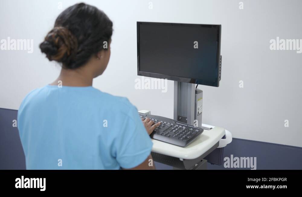 Female nurse types on electronic medical record chart in hospital ...