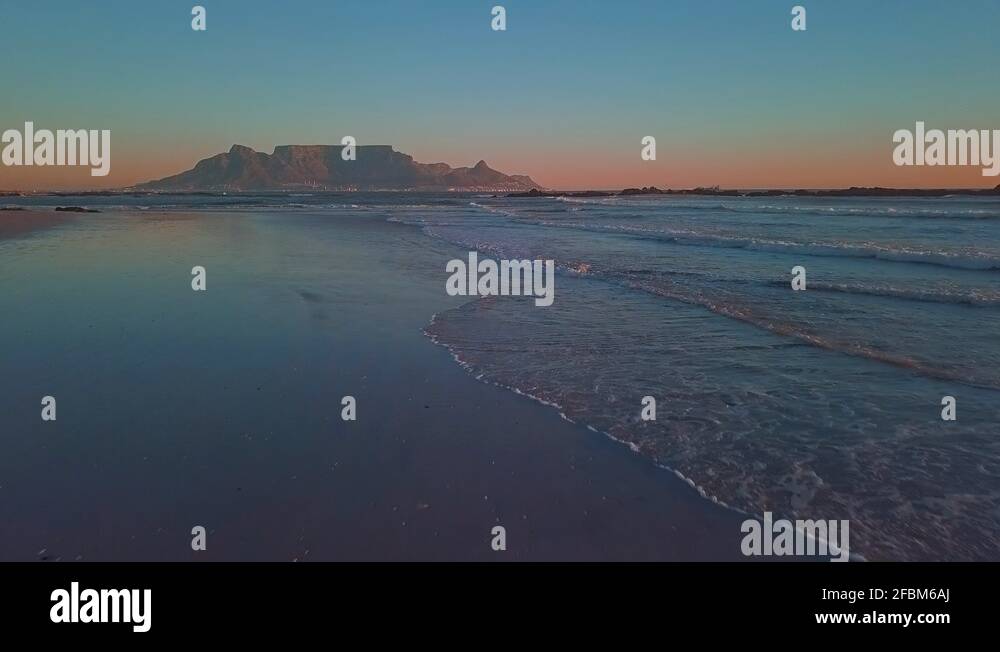 Cinematic wide low shot tracking over beach water from drone of Table ...