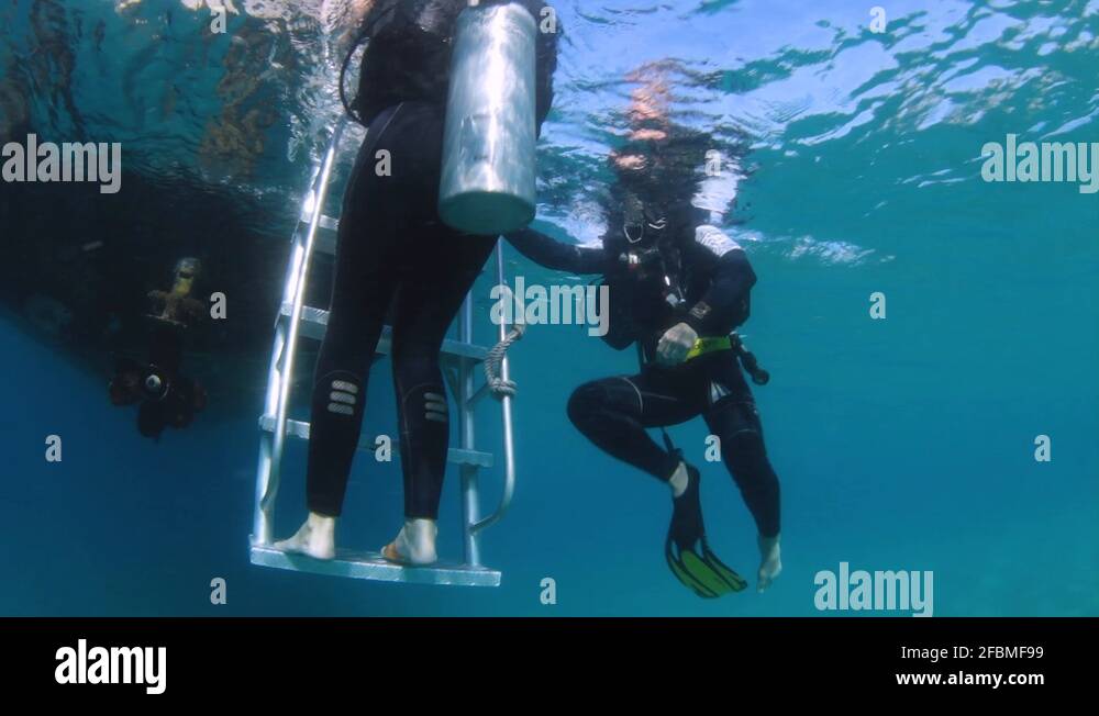A underwater view of scuba divers entering a boat using a ladder Stock ...