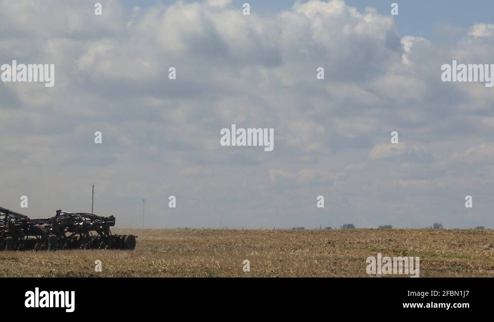 Agriculture, tractor and seeder planting canola, spring through frame ...
