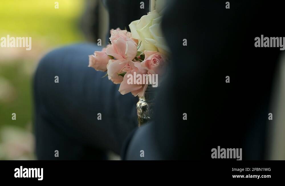 Knees and legs in church wedding aisle with pink and white flower vase ...