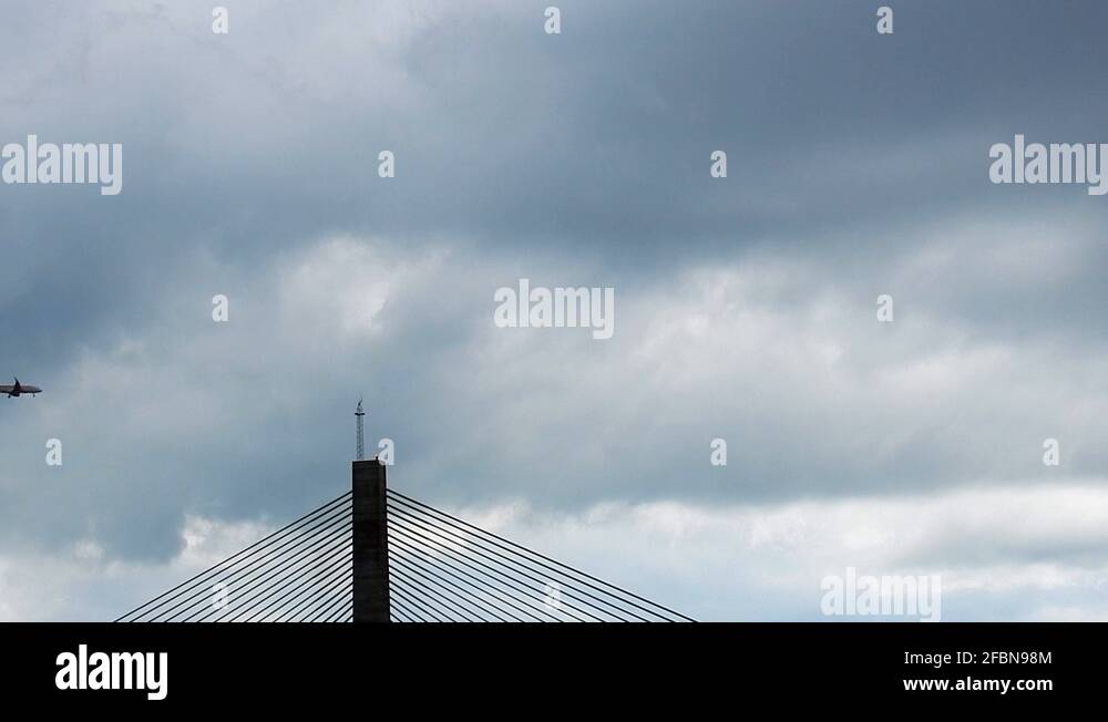 Aeroplane passing behind urban tower bridge structure on landing ...