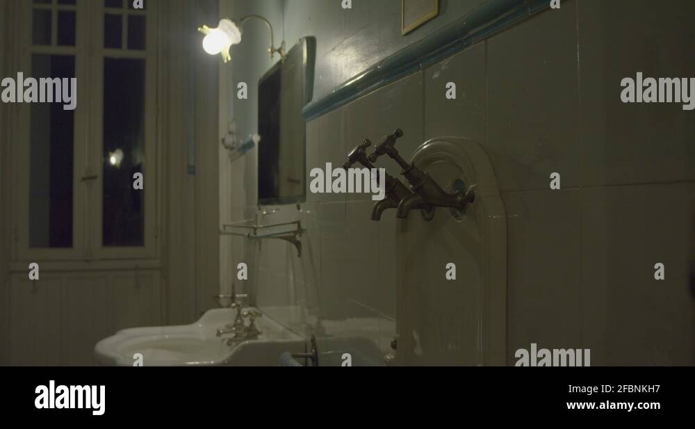 Water drop flowing from an old faucet in a scary old bathroom of a ...