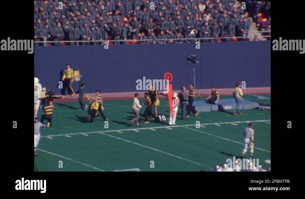 1970s: Football field. Cheerleaders in yellow & black flip and cheer. A ...