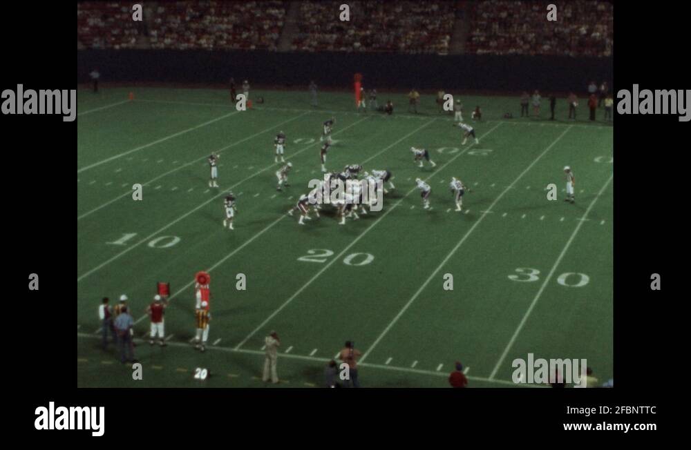 1970s: Football field. Teams at the 18 yard line. The ball is thrown ...