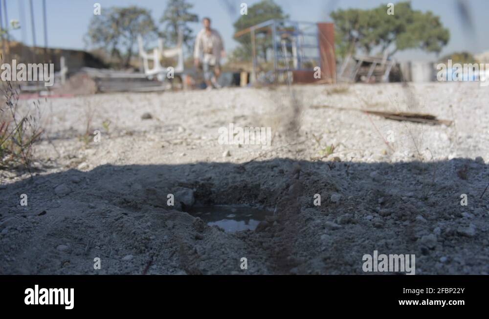 Thirsty homeless man running to a puddle to get a sip of rain water in ...
