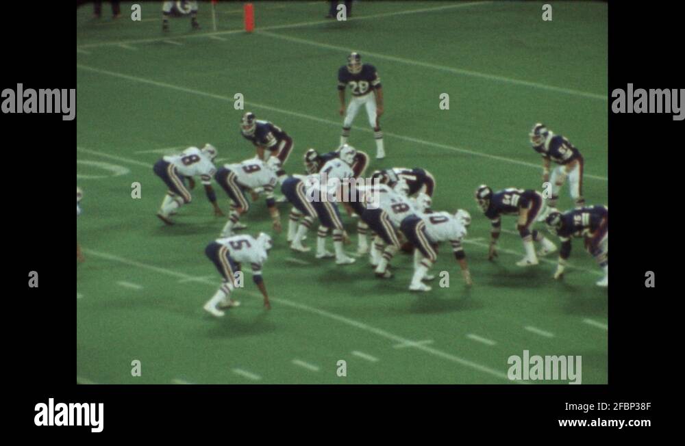 1970s: Football field. Teams on the 10 yard line. The quarterback gets ...