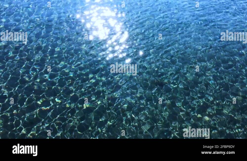 Sun rays in clear blue sea water. Ocean water surface texture and ...