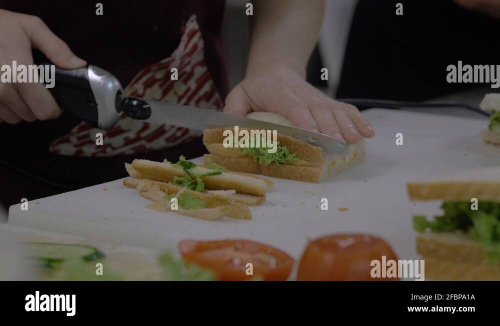 Cutting a club sandwich with electric knife. Ring crusts and cutting to ...