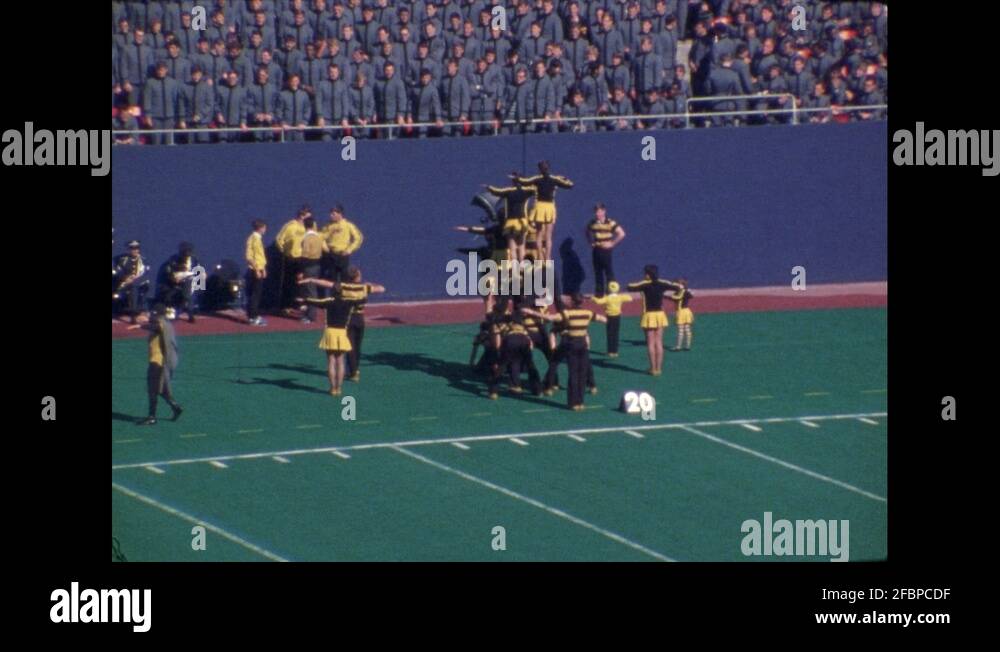 1970s: Football field sidelines. Cheerleaders in yellow & black in ...