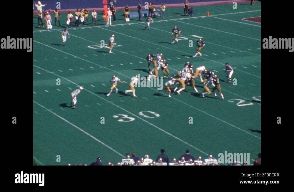 1970s: Football Field. 2 football plays. Play one is a hand-off into a ...