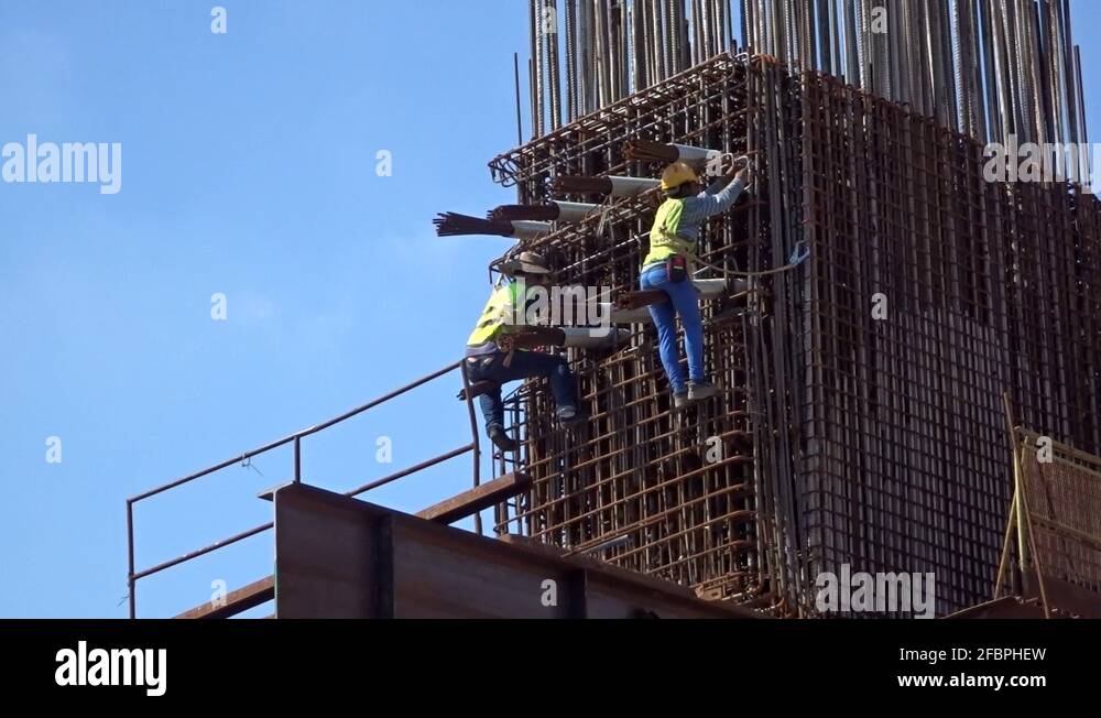 Construction workers working at height fabricating steel reinforcement ...